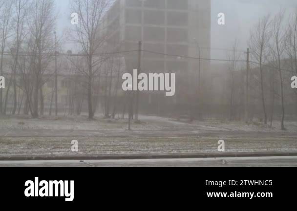 Snow and wind in spring. Blizzard into the city through the car glass ...