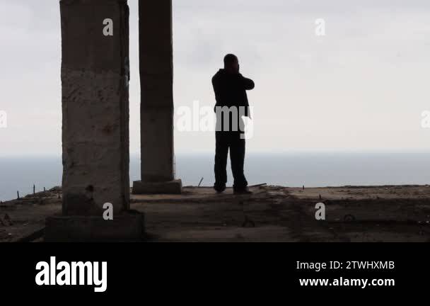 Silhouette of a sad man standing on the edge of a tall building. Mature ...