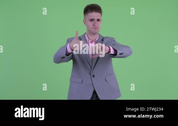 Confused young businessman choosing between thumbs up and thumbs down ...