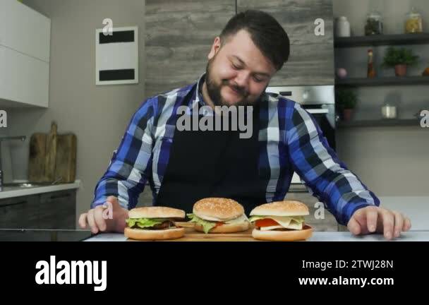 A funny thich guy is happy about hamburgers he cooked. Smile on the ...