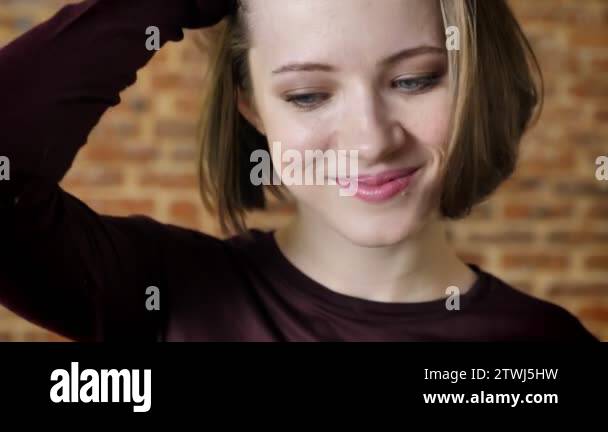Young Attractive Shy Girl Is Smiling Look Away Tucking Hair Watching At Camera Brick