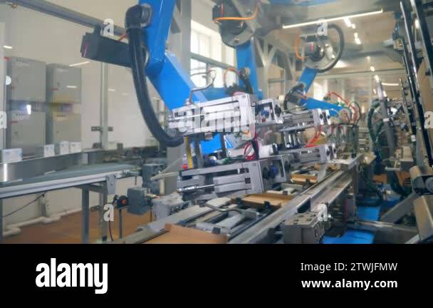 Factory machine puts cardboard sheets on a conveyor to make a box ...