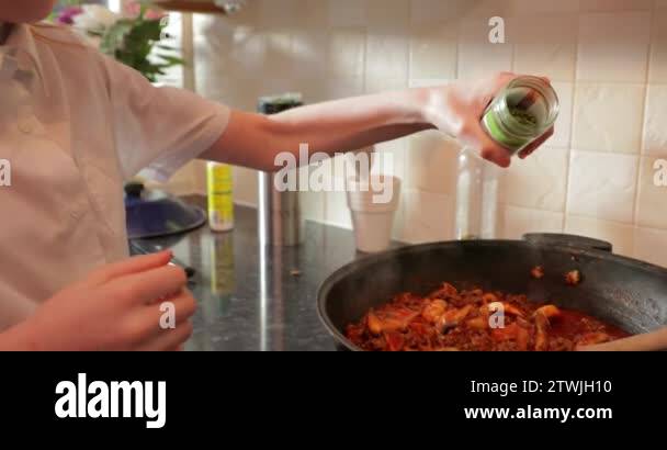 Little girl is helping her father to make a bolognese at home. She is ...