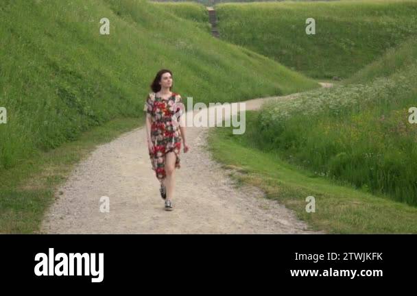 Girl in dress walk through rural gravel path between mounds Stock Video ...