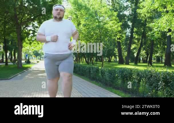 Purposeful fat man running in park, out of breath, persistent ...