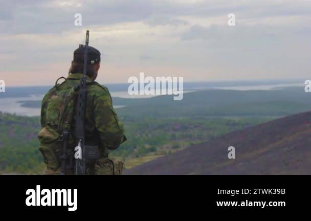 Army soldier with Sniper rifle in action in mountains. Back view. Look ...