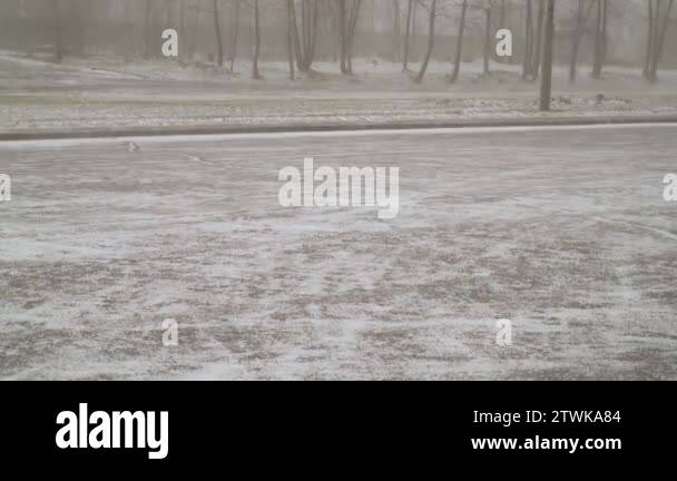 Snow and wind in spring. Blizzard into the city through the car glass ...