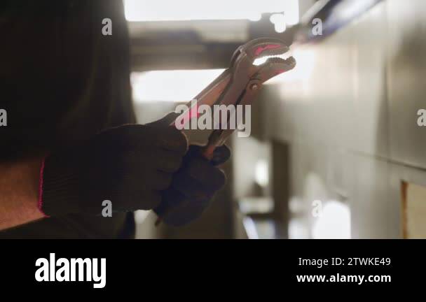 Mechanic stands in a car pit under lifted vehicle and prepares his ...