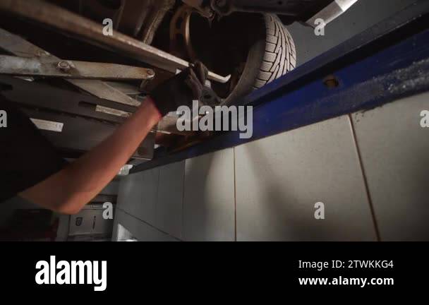 Mechanic stands in the pit and checks suspension at the car service ...