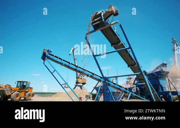 Mining industry concept. Crushed stones falling from a moving line at a ...