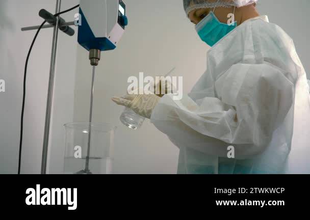Chemist mixing viscous liquid in a flask with a glass tube. Laboratory ...