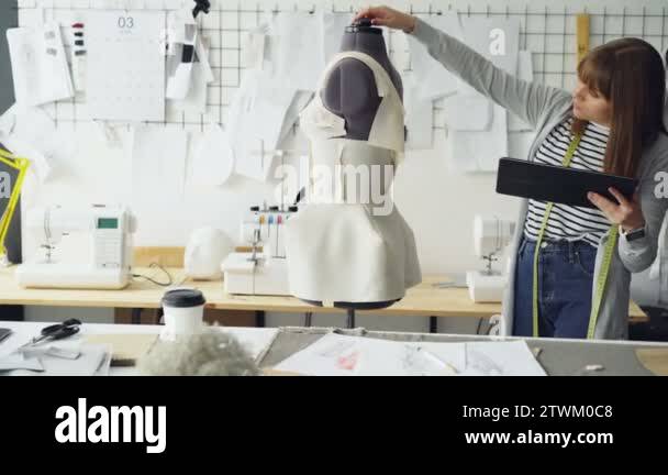 Beautiful tailor is turning tailoring dummy to check pinned clothing ...
