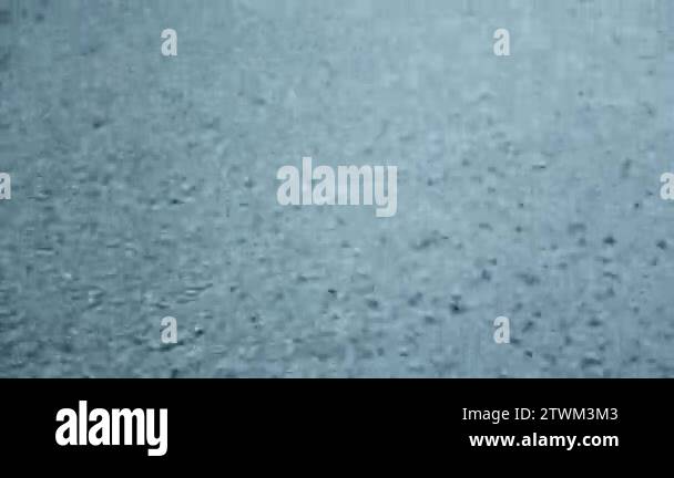 Rain drops fall on water surface of pond, lake or river forming a ...