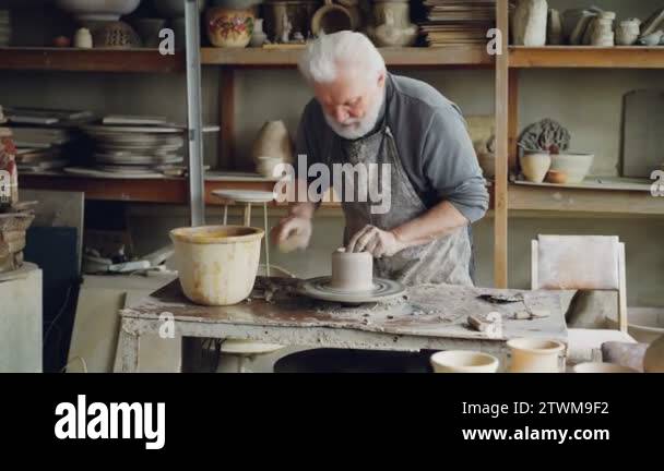 Senior man professional potter is making bowl from clay on spinning ...