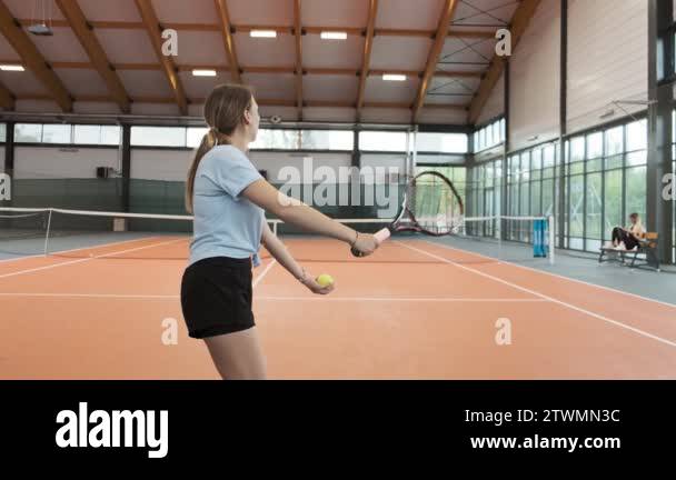 Young woman hitting tennis ball with racket. Female tennis player in ...
