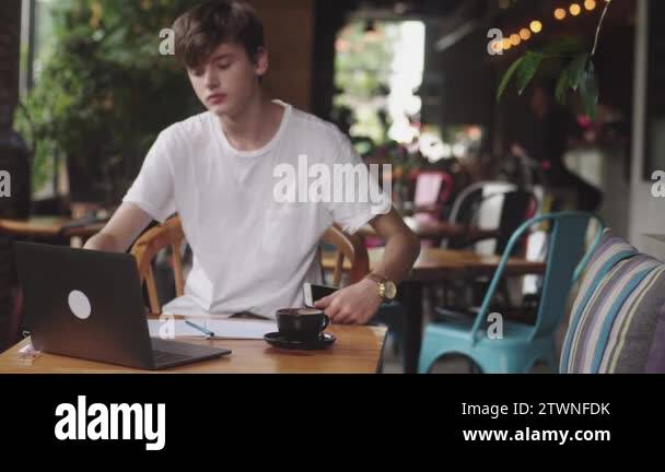 Young student doing homework in cafe, freelancer using pencil to draw ...