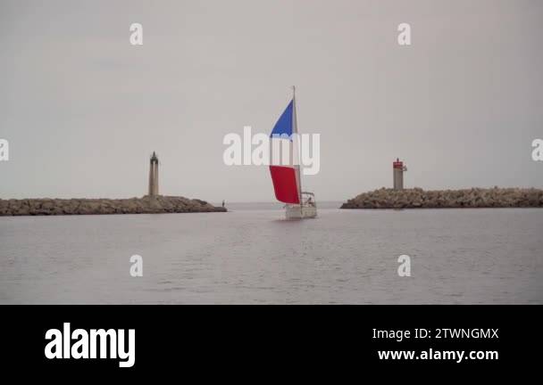 France flag sailing yacht sailing at a port between two lighthouses ...