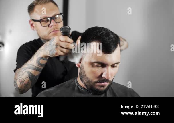 Barber whisks away sheared hairs from customers shoulders by brush ...