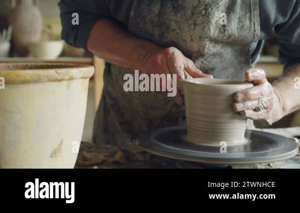 Close-up shot of half-finished ceramic vase spinning on potterss wheel ...