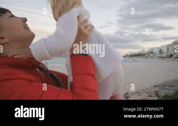 Attractive woman with baby on the evening seafront. Close-up of mom ...