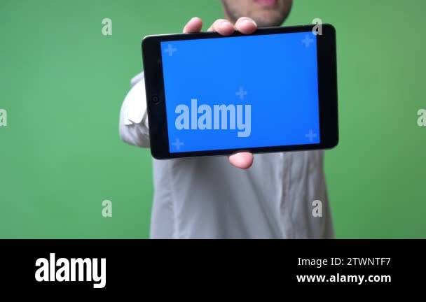 Man in white shirt showing tablet with chroma key at camera and ...
