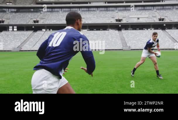 Side view of male rugby players playing rugby match in stadium. They ...