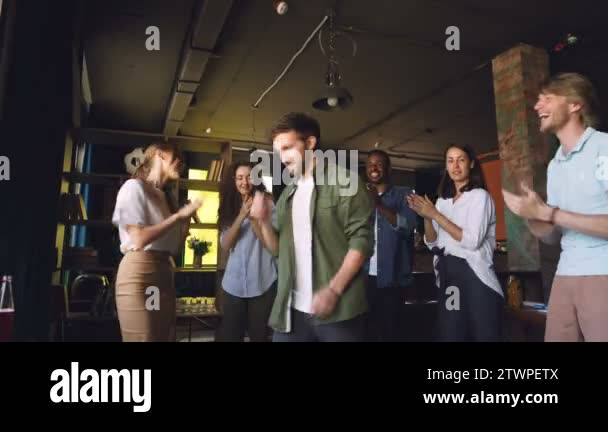 Happy young people are dancing in circle at office party, clapping ...