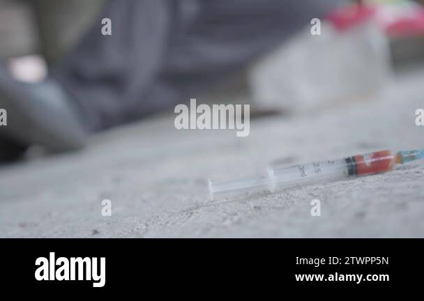 Close-up of syringe with blood inside lying on the concrete floor. The ...