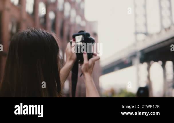 Back view happy female tourist with camera takes photos of Brooklyn ...