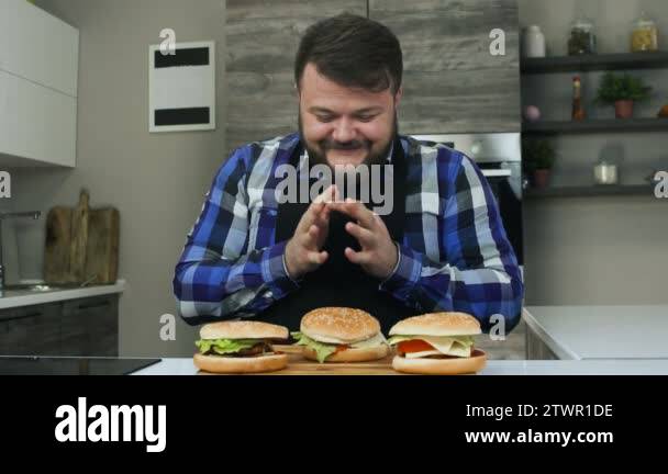 Satisfied plump man is happy about hamburgers he cooked. Smile on the ...