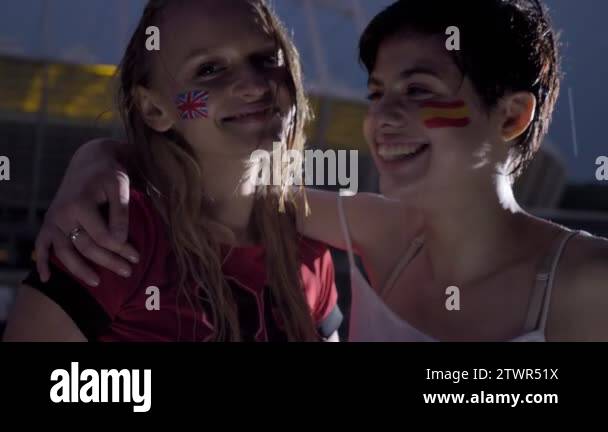 Two young girls, football fans in rain, England and Spain, smiling ...