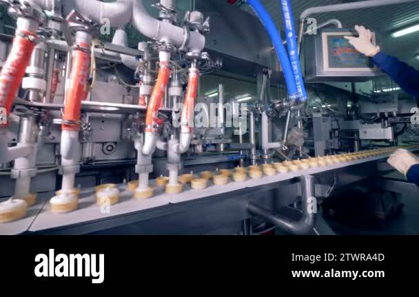 Industrial machine is filling wafer cups with white ice-cream while a ...