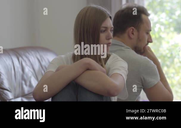 Portrait of sad man and woman sitting back to back with unhappy faces ...