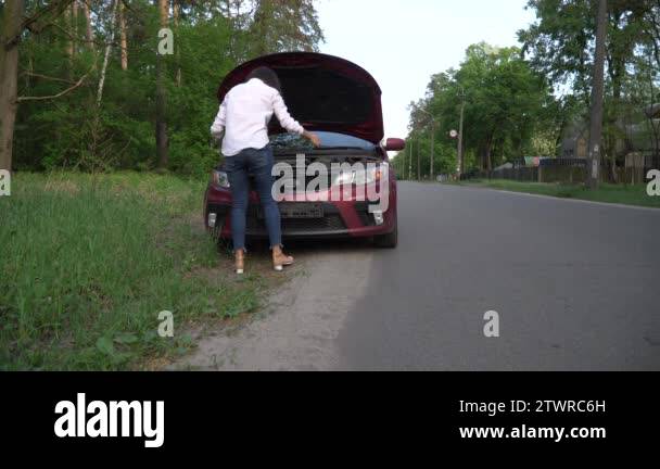 Elegant woman exit from vehicle and opening the hood, broken down car ...