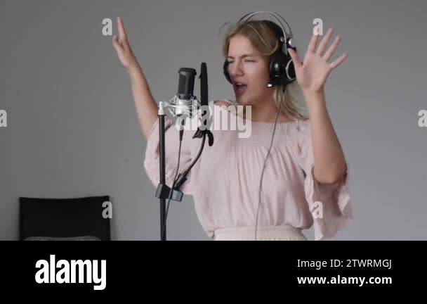 Beautiful blonde singer girl in headphones at home recording studio ...