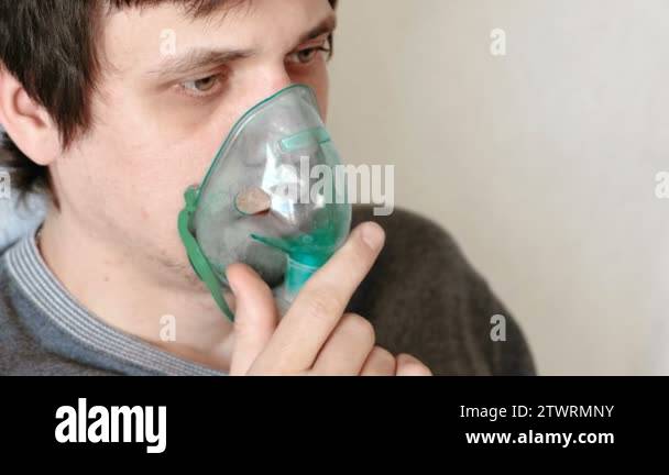 Use nebulizer and inhaler for the treatment. Closeup mans face inhaling ...