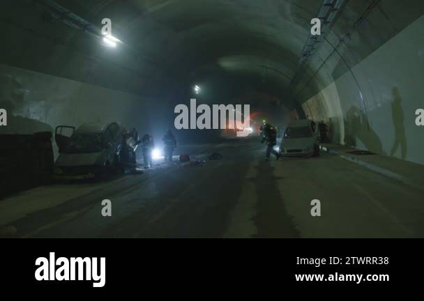 Car accident scene inside a dark tunnel, firefighters rescuing people ...