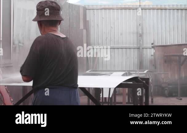 Man applying anti-corrosion powder coating metal sheet with spray gun ...