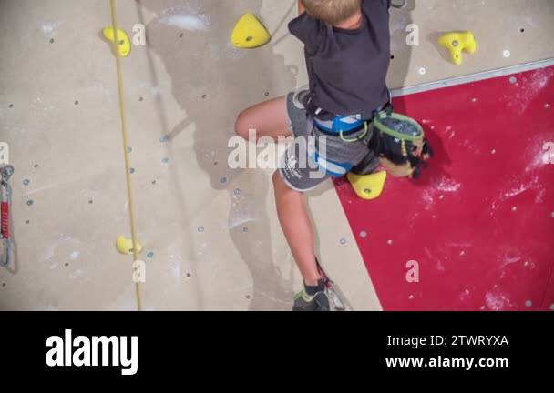 A young student tries to climb to the very top of the climbing wall. He ...