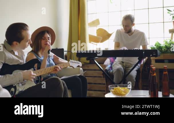 Smiling musicians members of popular band are rehearsing at home ...