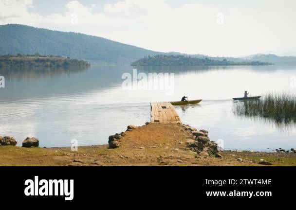 Two men paddling in dugout canoes together in a mountain lake Stock ...
