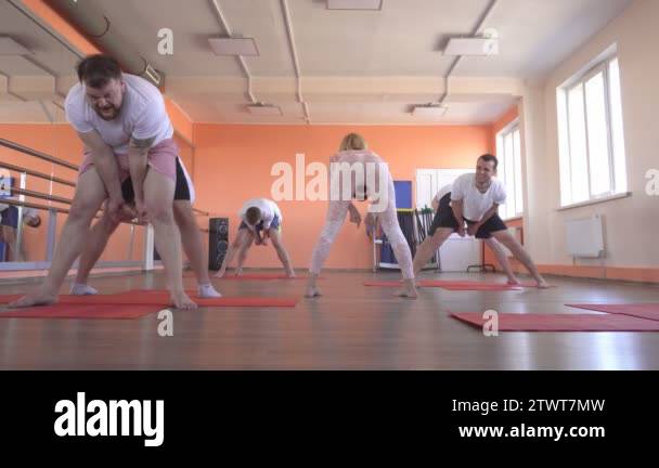 Beautiful caucasian female instructor teaches yoga techniques in a male ...