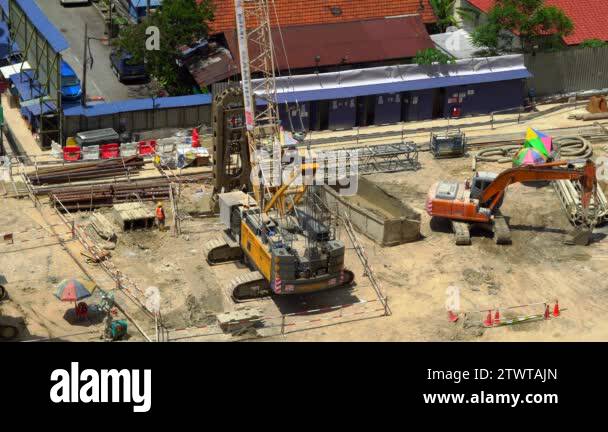 excavator digging holes for foundation of building construction site ...