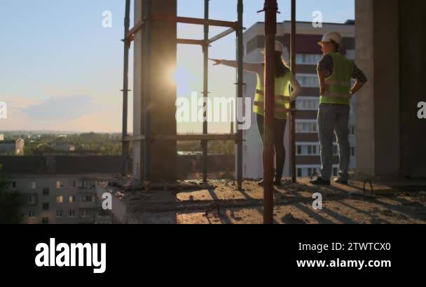 Woman architect and man builder at construction site, back view ...