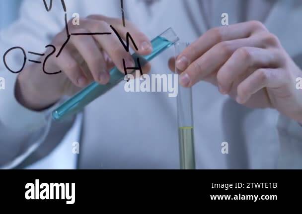 Chemist mixing various reagents guided by written formula, chemical ...