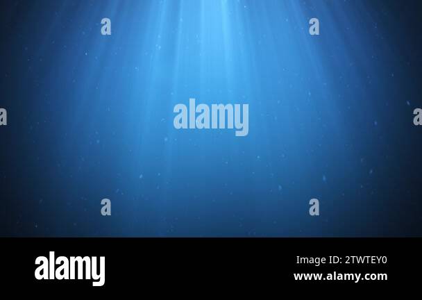 Rays of sunlight shining from above penetrate deep clear blue water ...