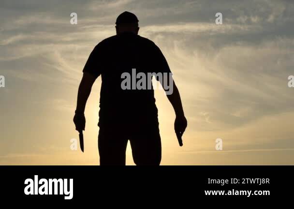 man surrender and drops knife and pistol silhouette at sky background ...