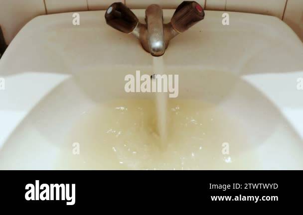 Wash basin full of dirty water / Dirty water flows from the tap into ...