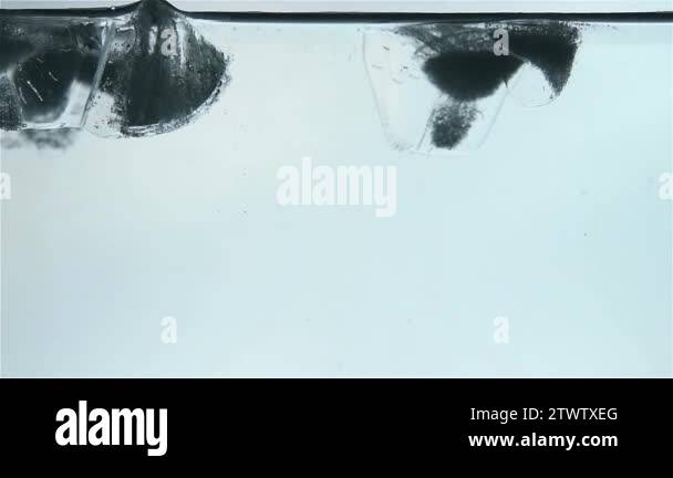 Clear ice cubes float and melt with bubbles of air in blue transparent ...