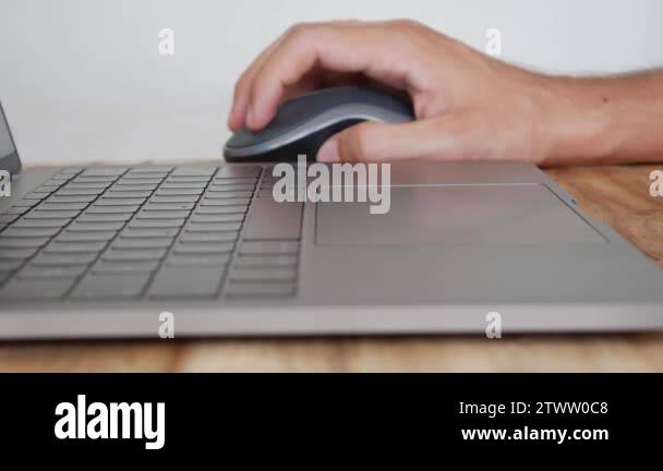 Hand using wireless mouse with laptop and types on the keyboard, personal computer use for ...